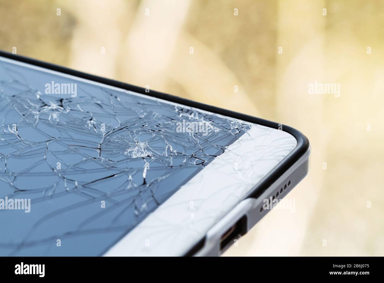 Smartphone with broken screen. Damaged phone glass. Closeup, yellow ...