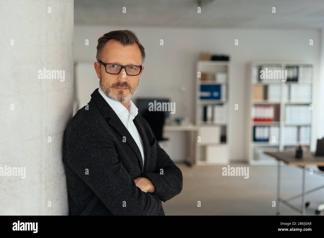 Authoritative determined businessman standing with folded arms looking ...