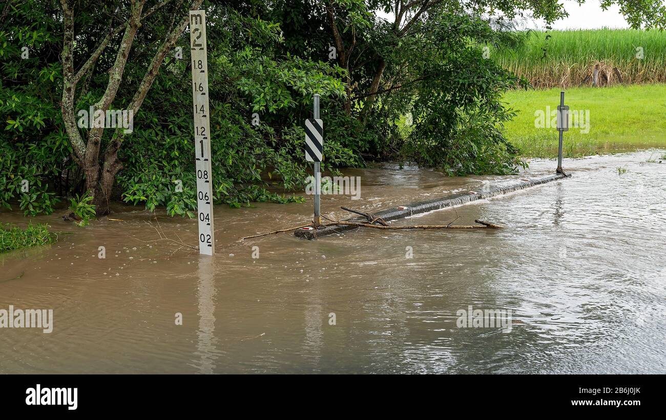Water over the road from an overflowing creek caused by heavy tropical ...