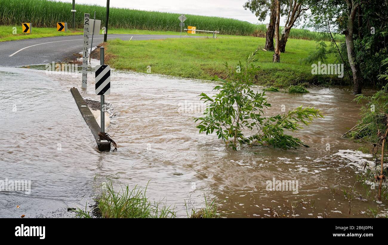 Water over the road from an overflowing creek caused by heavy tropical ...