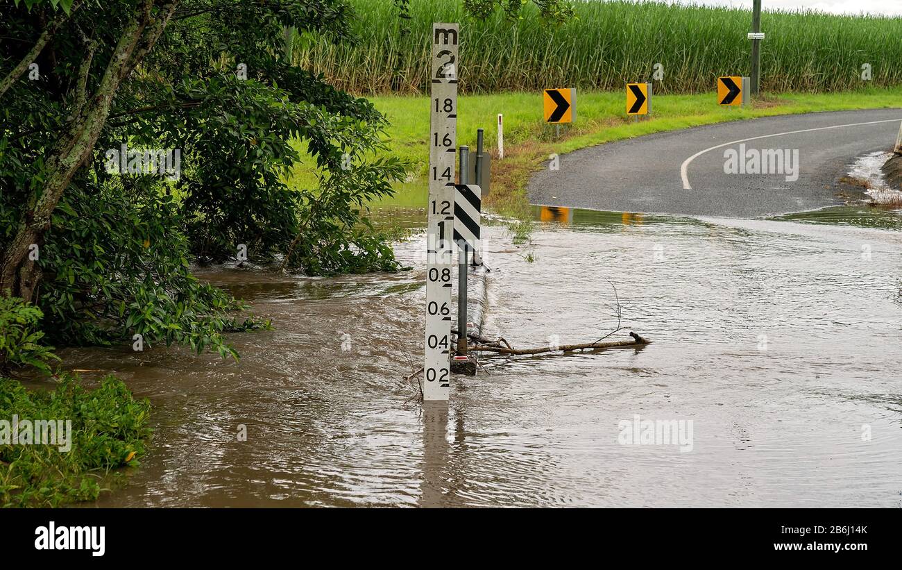 Water over the road from an overflowing creek caused by heavy tropical ...