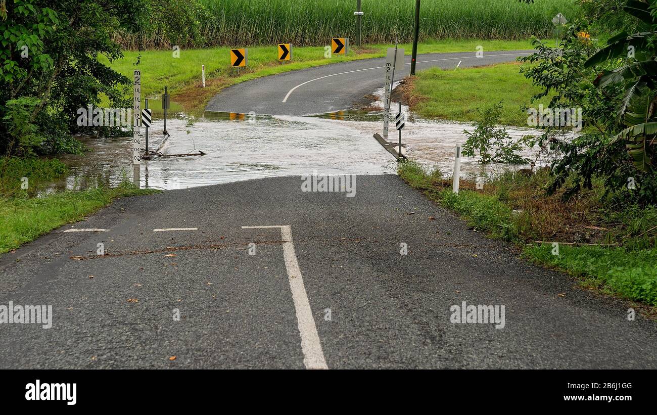 Water over the road from an overflowing creek caused by heavy tropical ...
