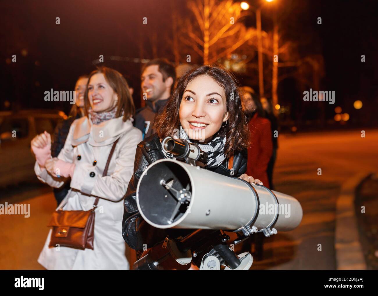 Group of people at night looks at the starry sky in a large ...