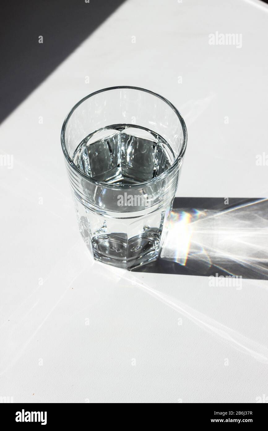 Water glass with strong shadows on white background Stock Photo - Alamy