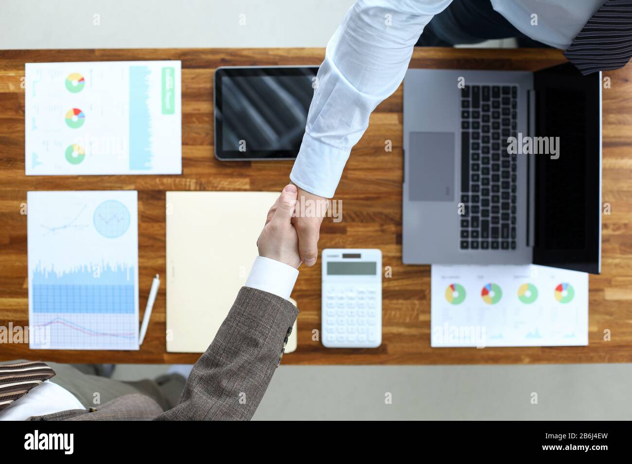 Men shake hands over table in office, contract Stock Photo - Alamy