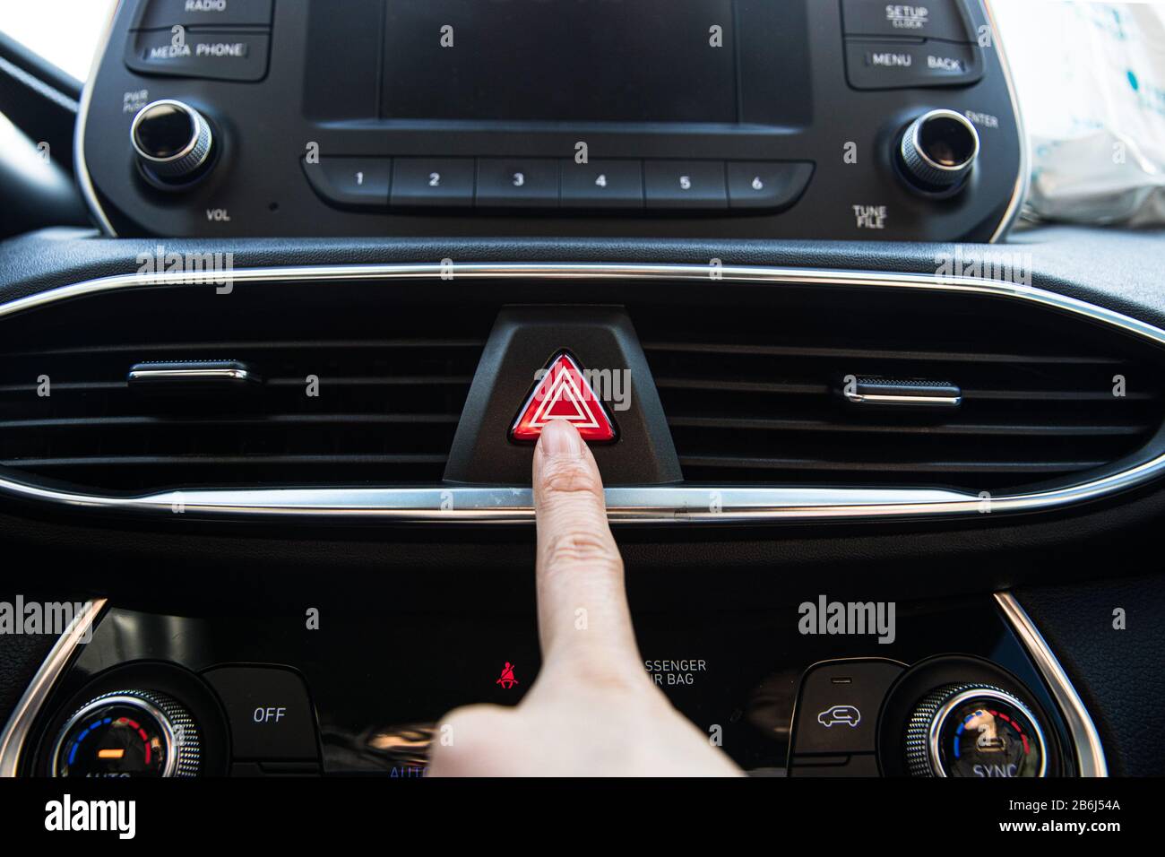 Finger pressing a hazard warning lights button on a modern luxury ...