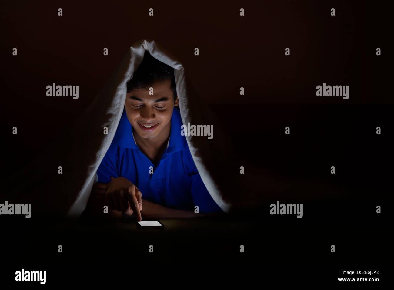 Teenage boy using his mobile phone in a dark room Stock Photo - Alamy