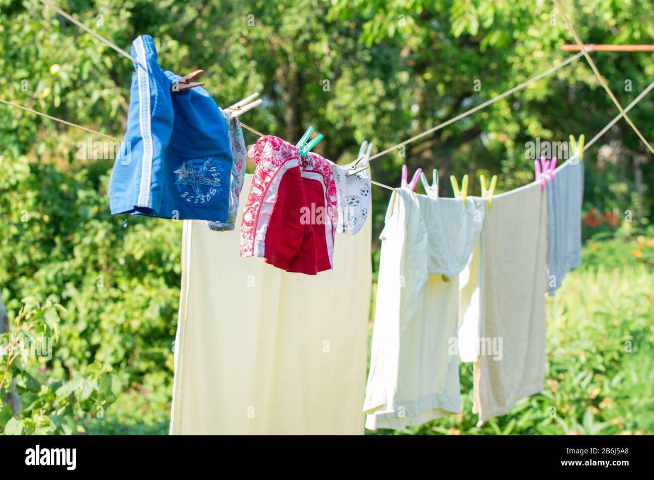 Clean laundry drying on line outside green background Stock Photo - Alamy