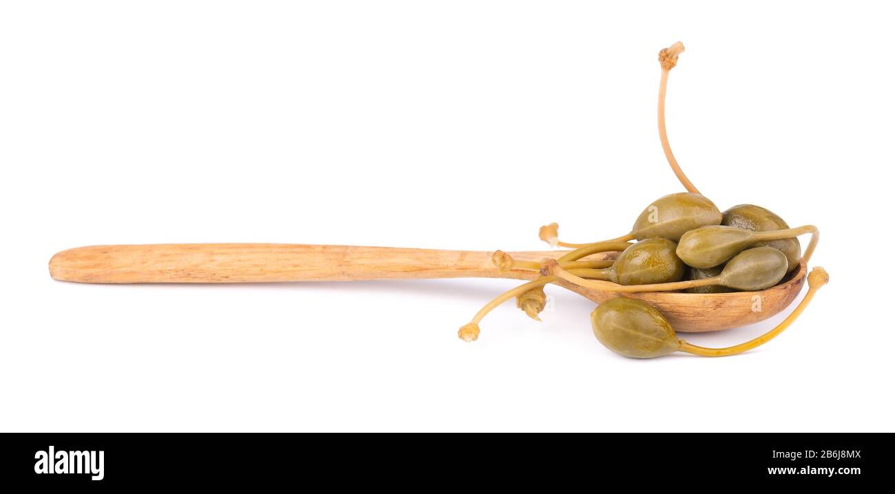 Capers in a wooden spoon, isolated on white background. Pickled capers ...