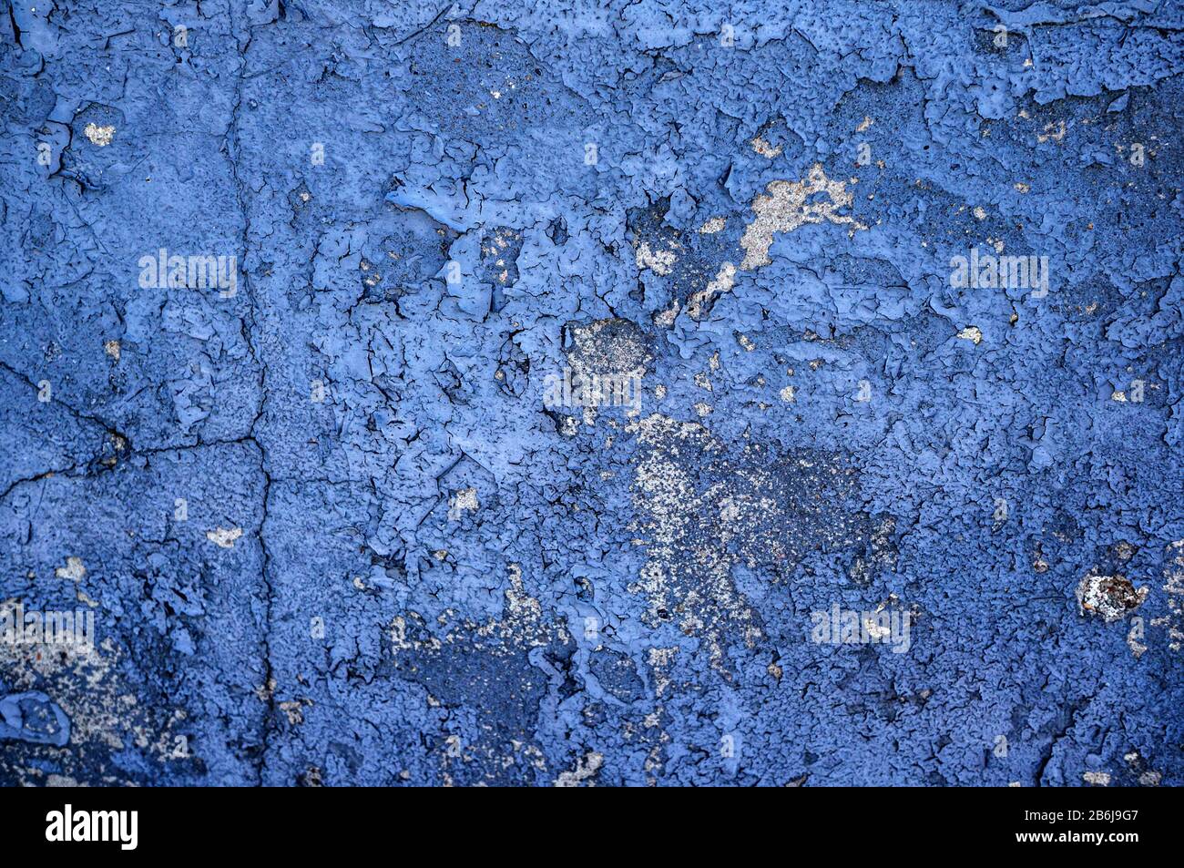 Blue painted cement wall with deep cracks from old age and ...