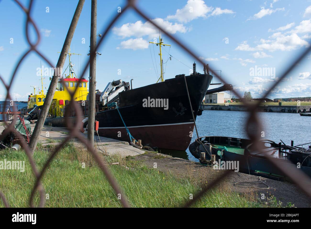 Ship in port behind metal grid fence Stock Photo - Alamy