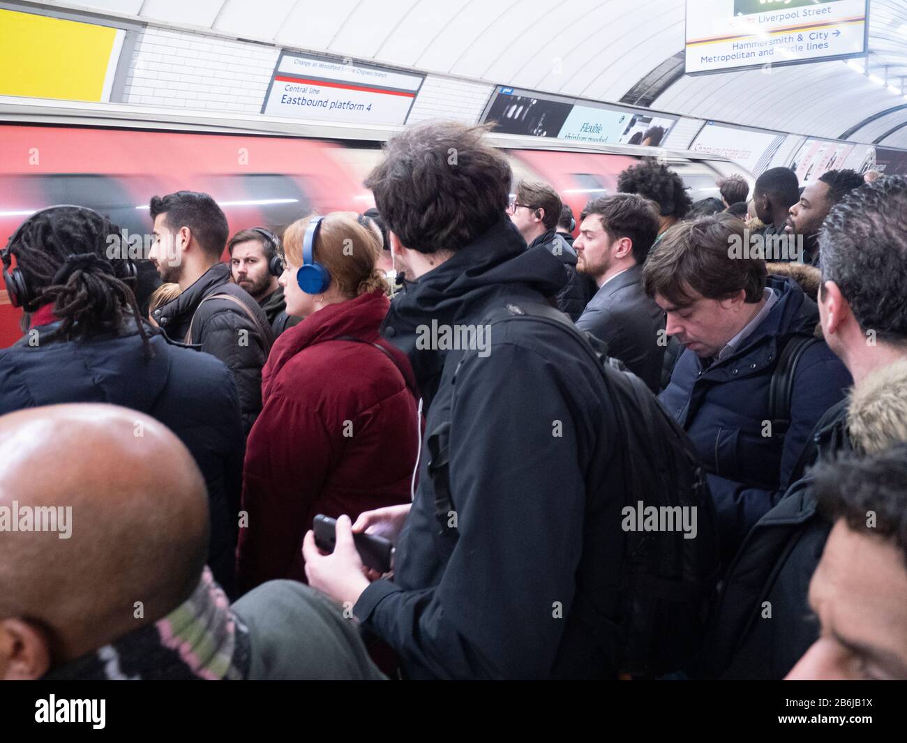 Packed London Underground tube platform with train arriving on platform ...