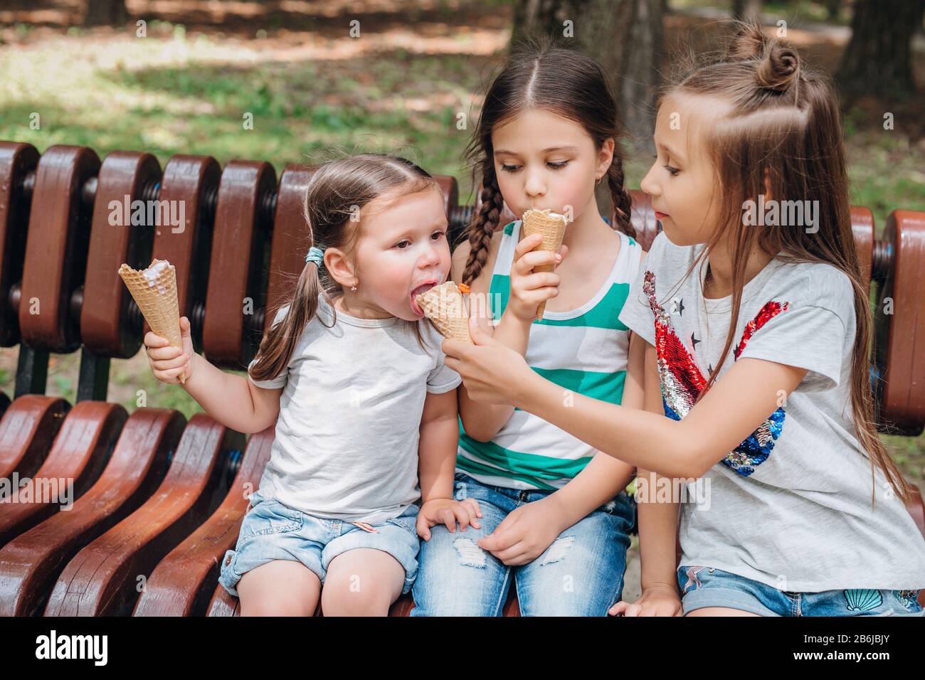 Happy children sitting and eating ice-cream in park Stock Photo - Alamy