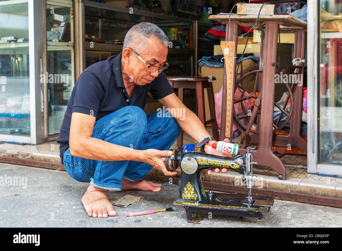 Man repairing an old styled sewing machine, Sandakan, Sabah district ...