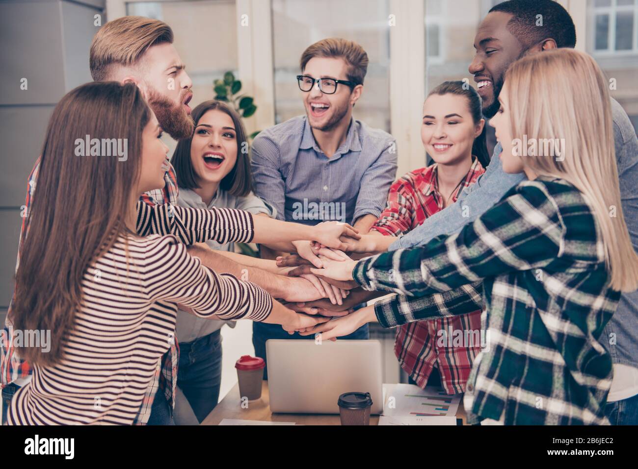 Happy multiethnic businesspeople working together and putting hands on ...