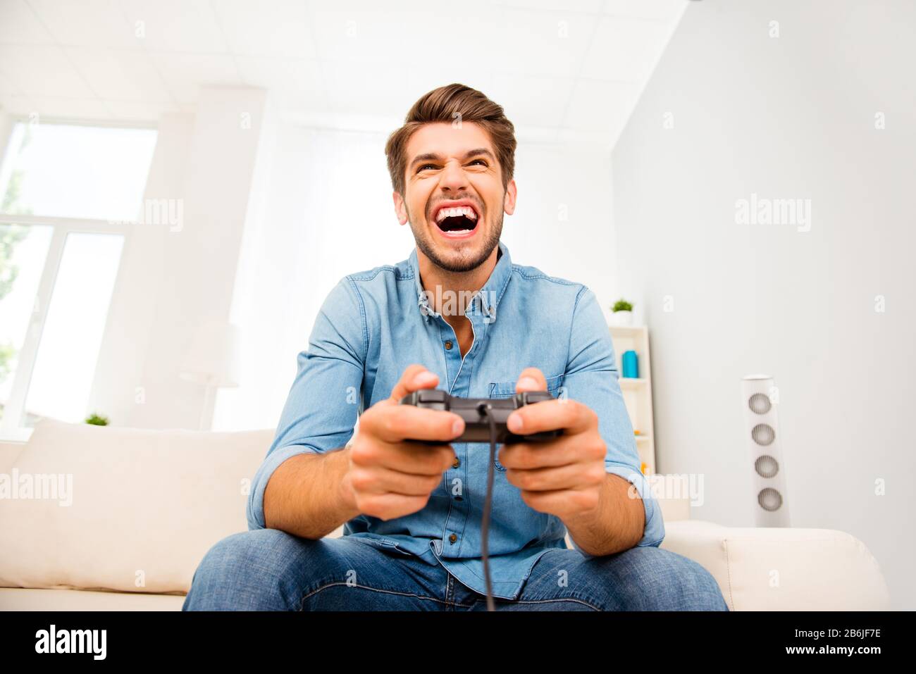 Young happy man laughing and playing video games on weekend Stock Photo ...