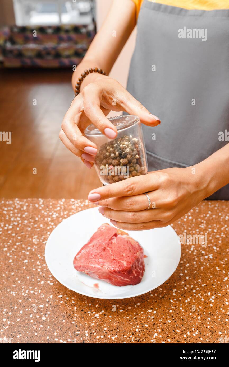 Woman chef in apron with Fresh beef steak on a kitchen table with ...