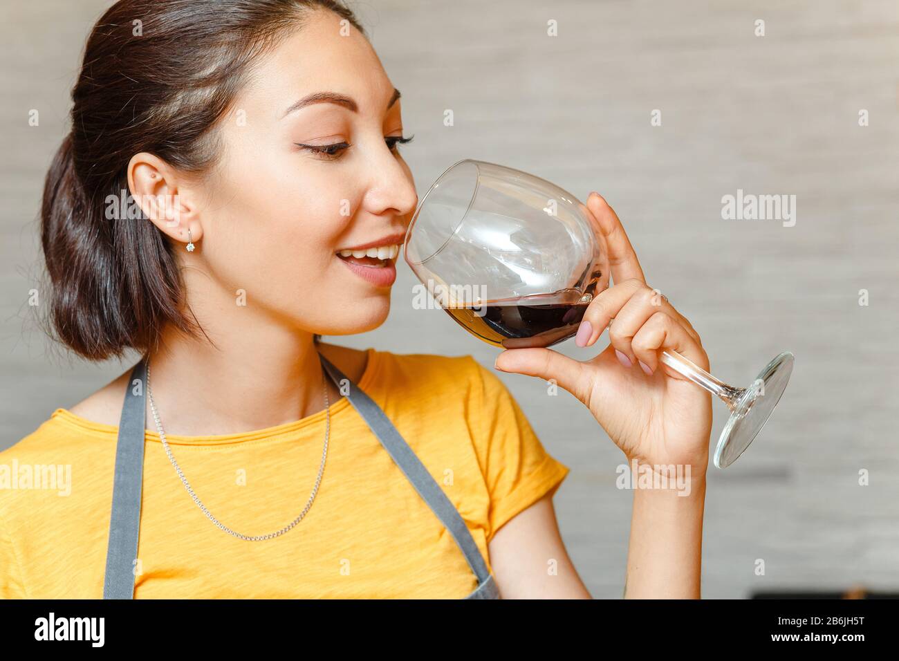 Asian woman sommelier in apron holding red wine glass Stock Photo - Alamy