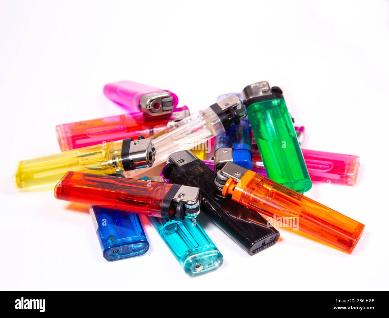 several lighters in different colors lying mixed up on white ...