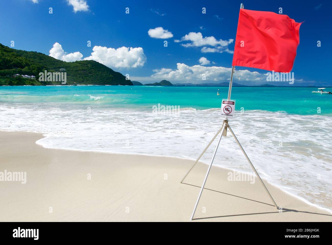 Bright sunny view of red flag standing in the waves of a tropical ...