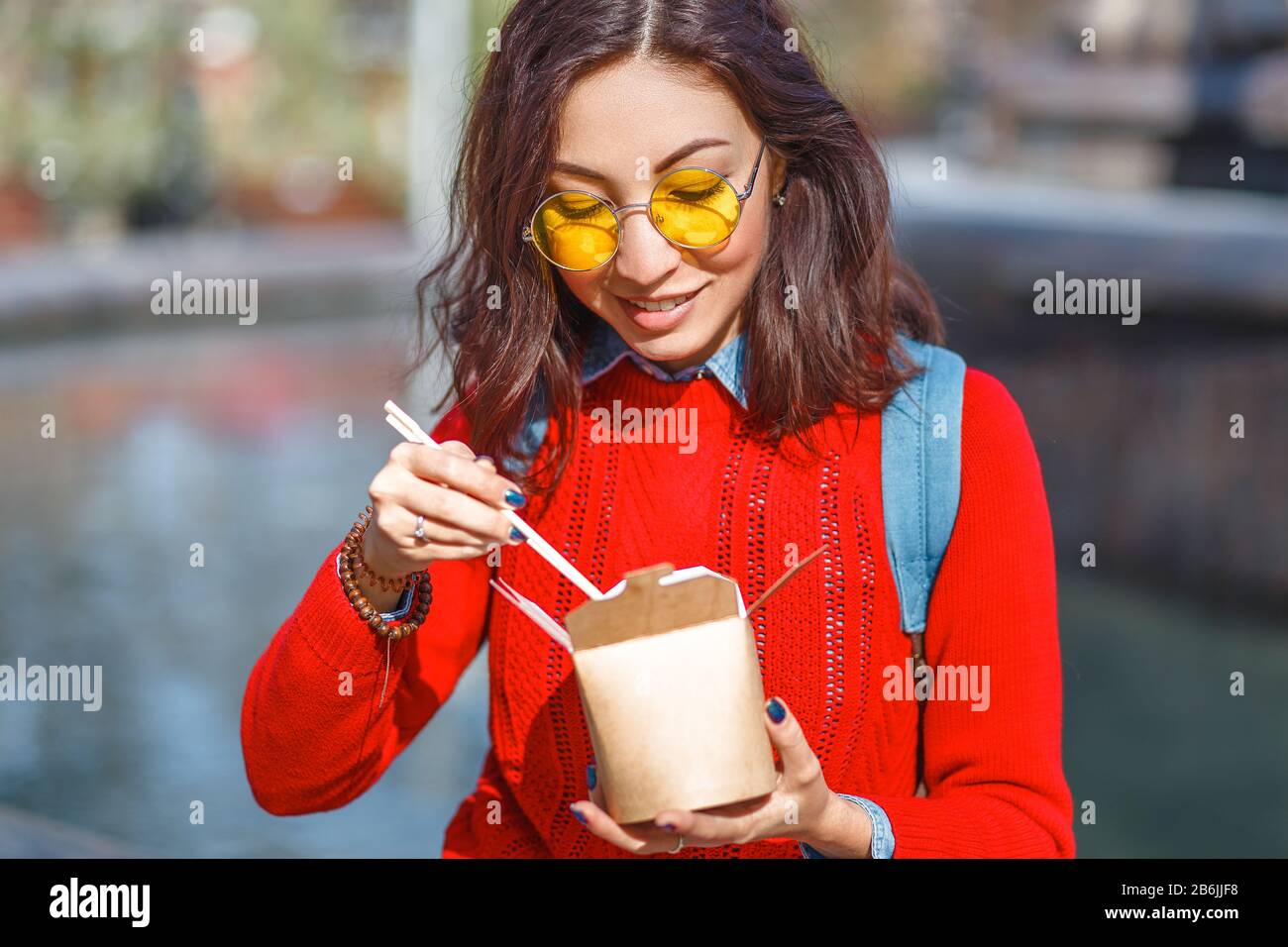 Asian Woman eating street food from takeaway paper box outdoors in Hong ...