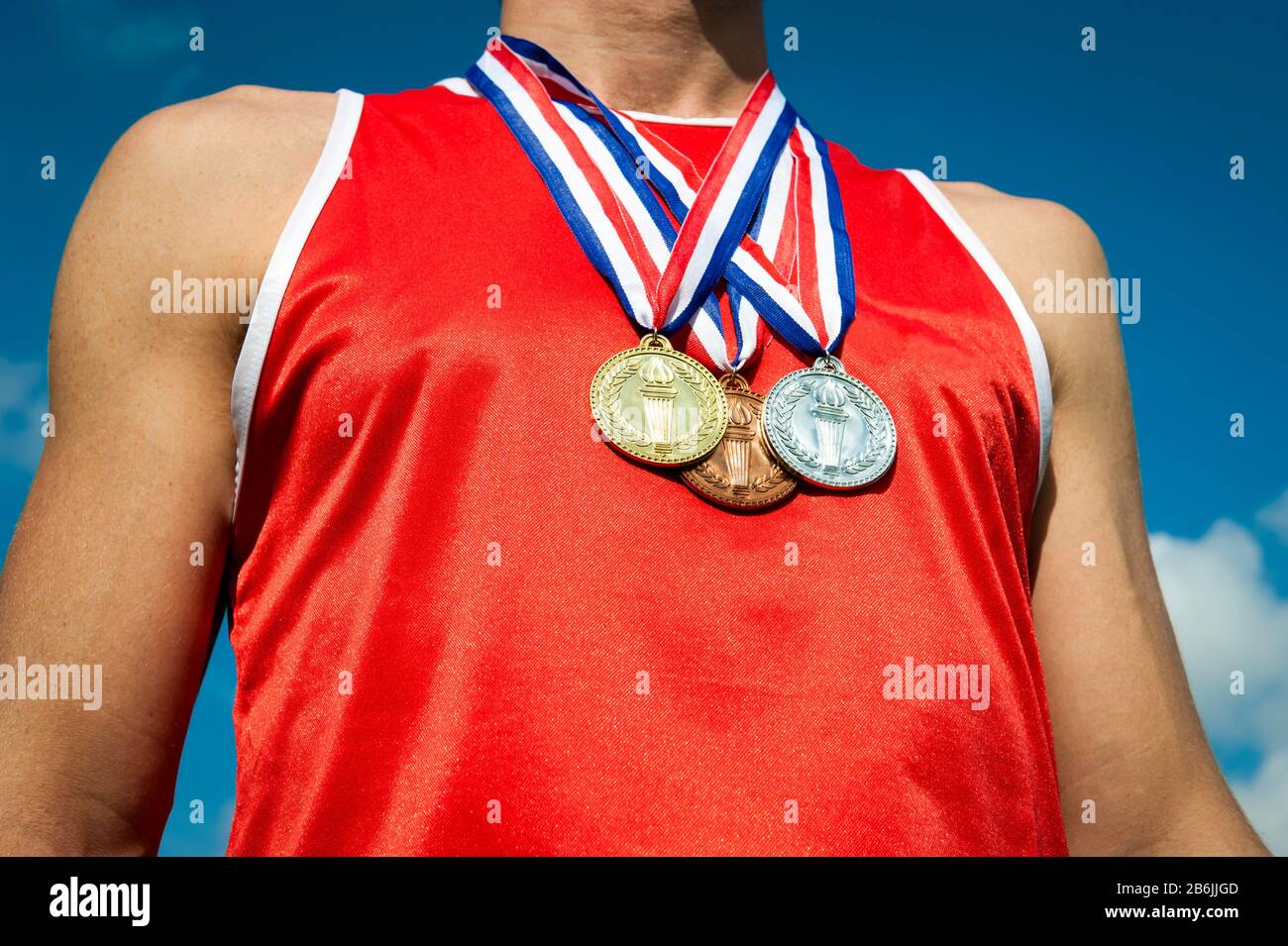 Unrecognizable male athlete showing off gold, silver, and bronze medals ...