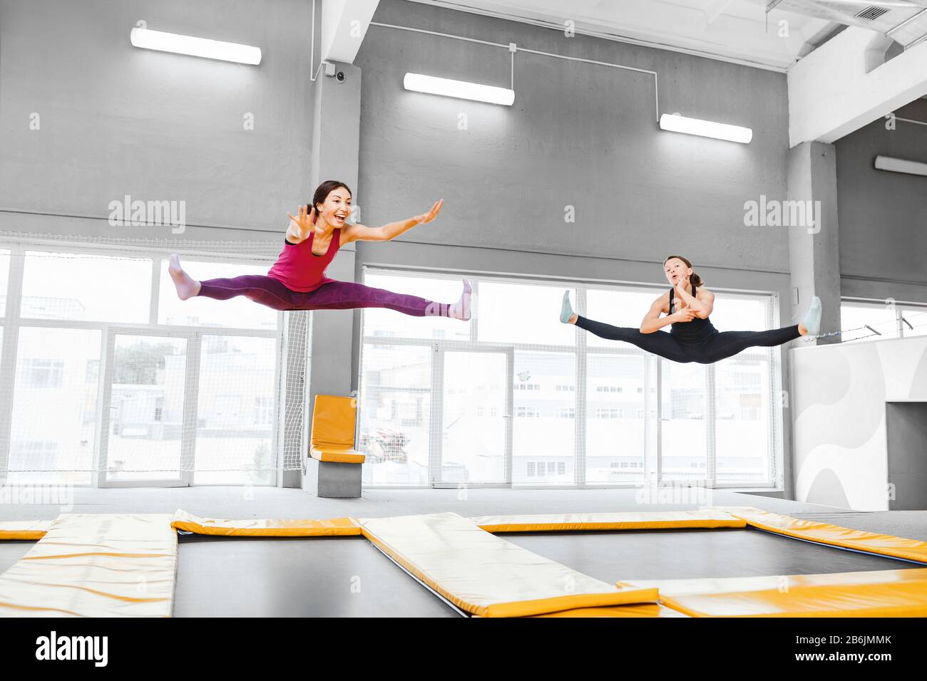 Two young active women jumping on trampolines in a modern fitness ...