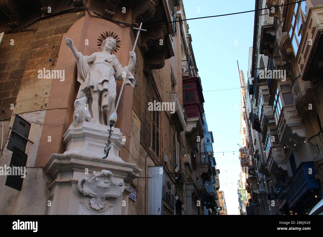 statue of holy character (st john) and flats buildings in valletta ...