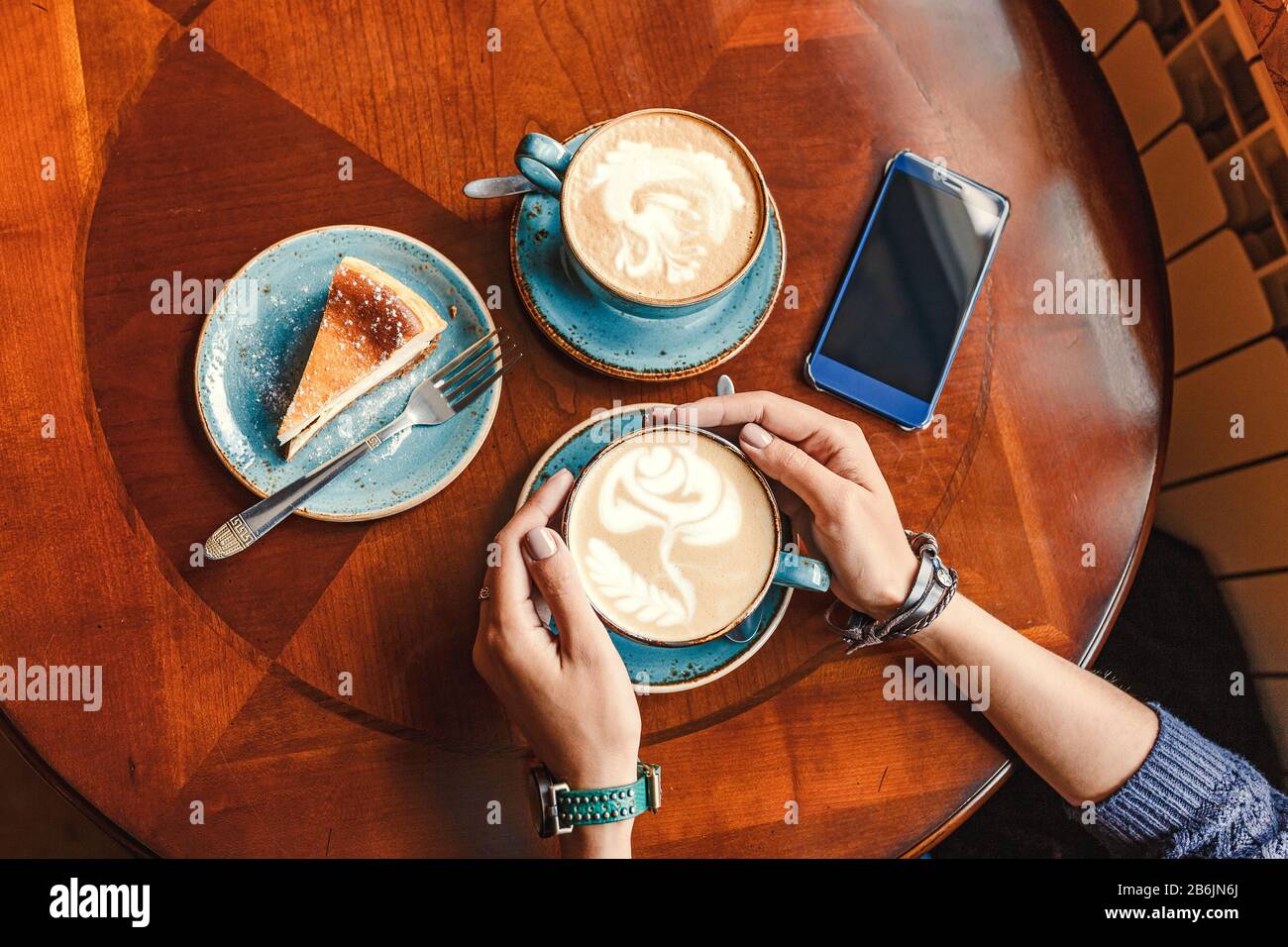 Flat lay photo of coffee cup, cheese cake and smartphone on table in a ...