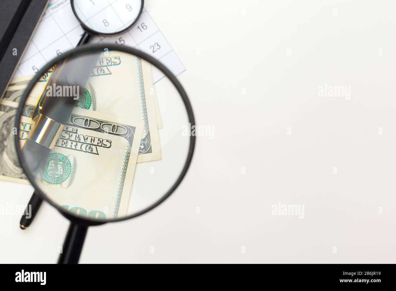 Magnifying glass and a pile of money Stock Photo - Alamy