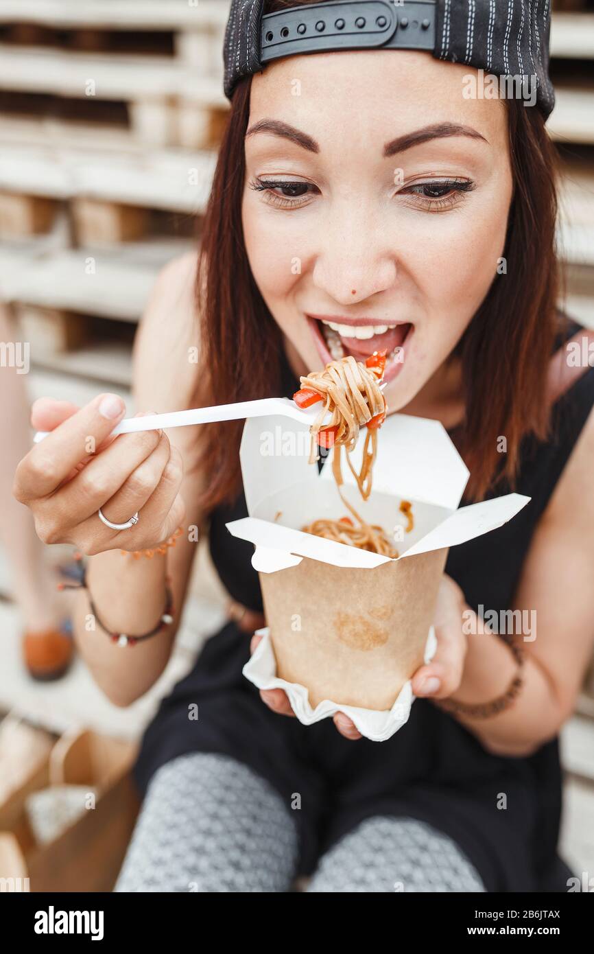 Young Woman Eating Asian wok Noodle Cuisine from Take away Box at the ...