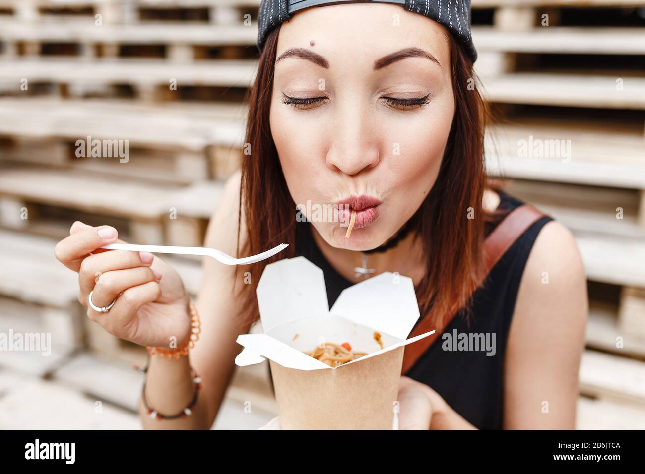 Young Woman Eating Asian wok Noodle Cuisine from Take away Box at the ...