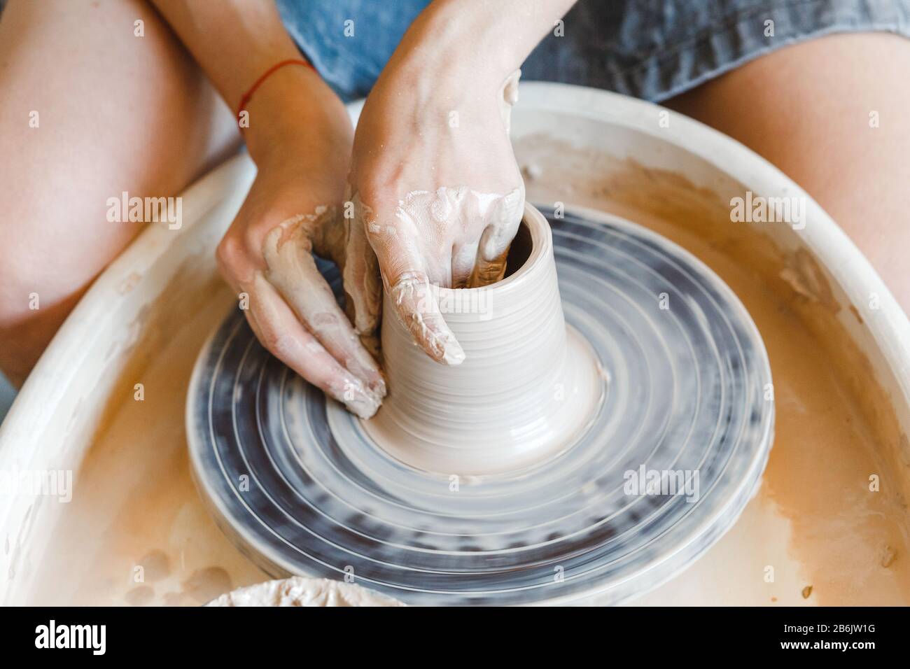 Top view of hands with clay making of a ceramic pot on the pottery ...