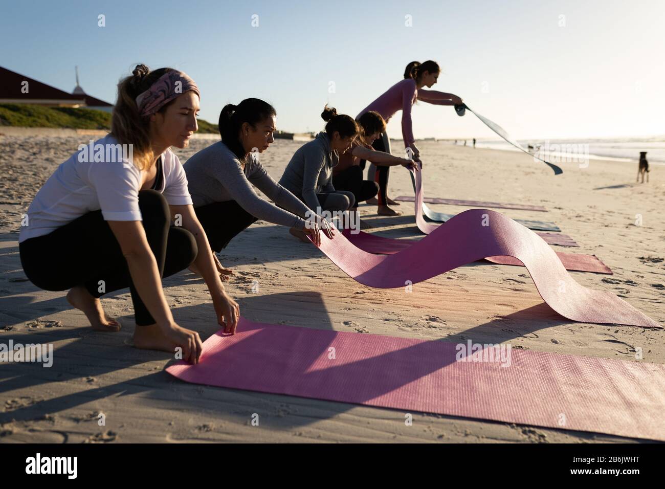 Side view of women installing their yoga mat on the sand Stock Photo ...