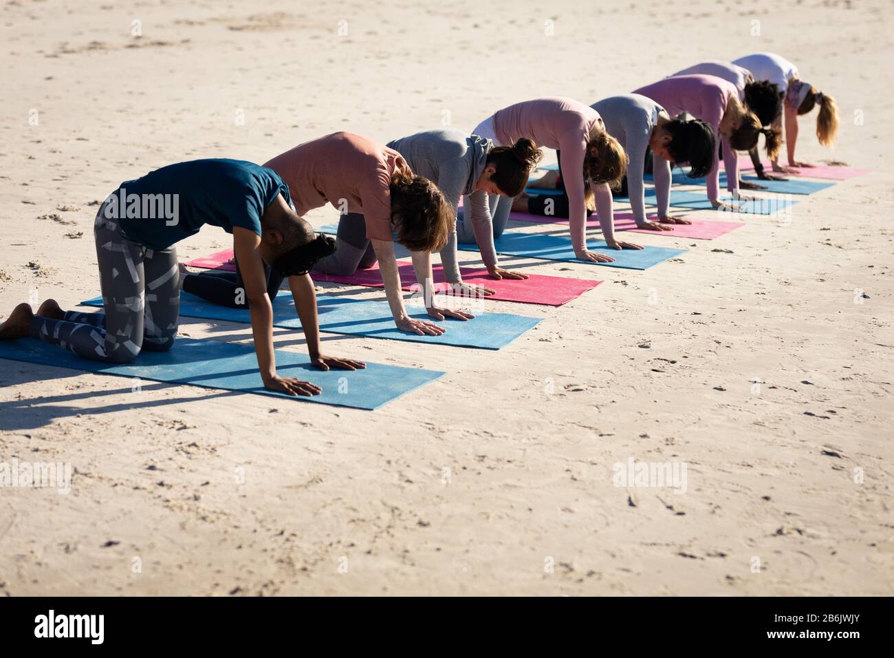 Side view of women doing yoga positions at the beach Stock Photo - Alamy