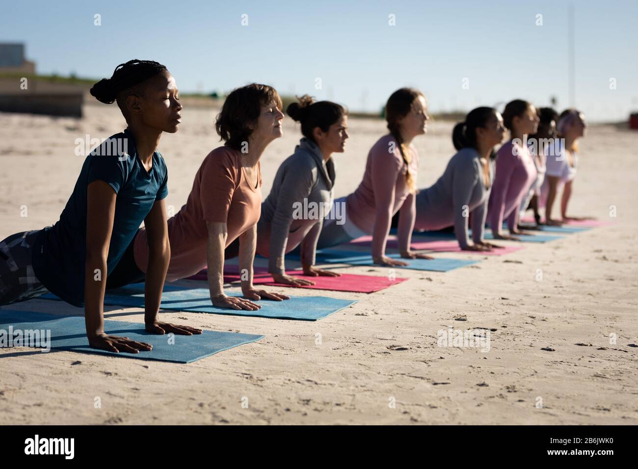 Side view of women doing yoga positions at the beach Stock Photo - Alamy