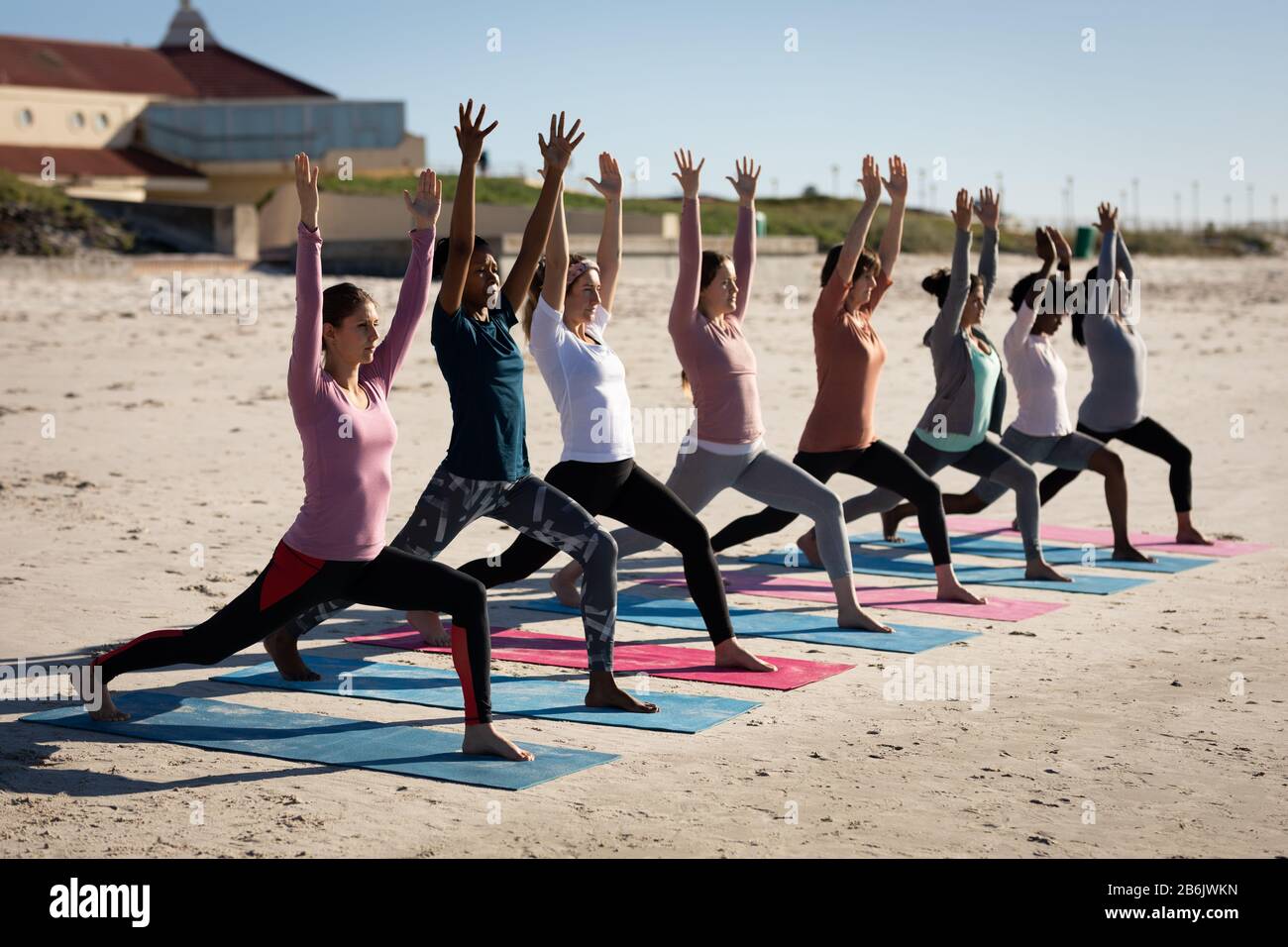 Side view of women doing yoga positions at the beach Stock Photo - Alamy