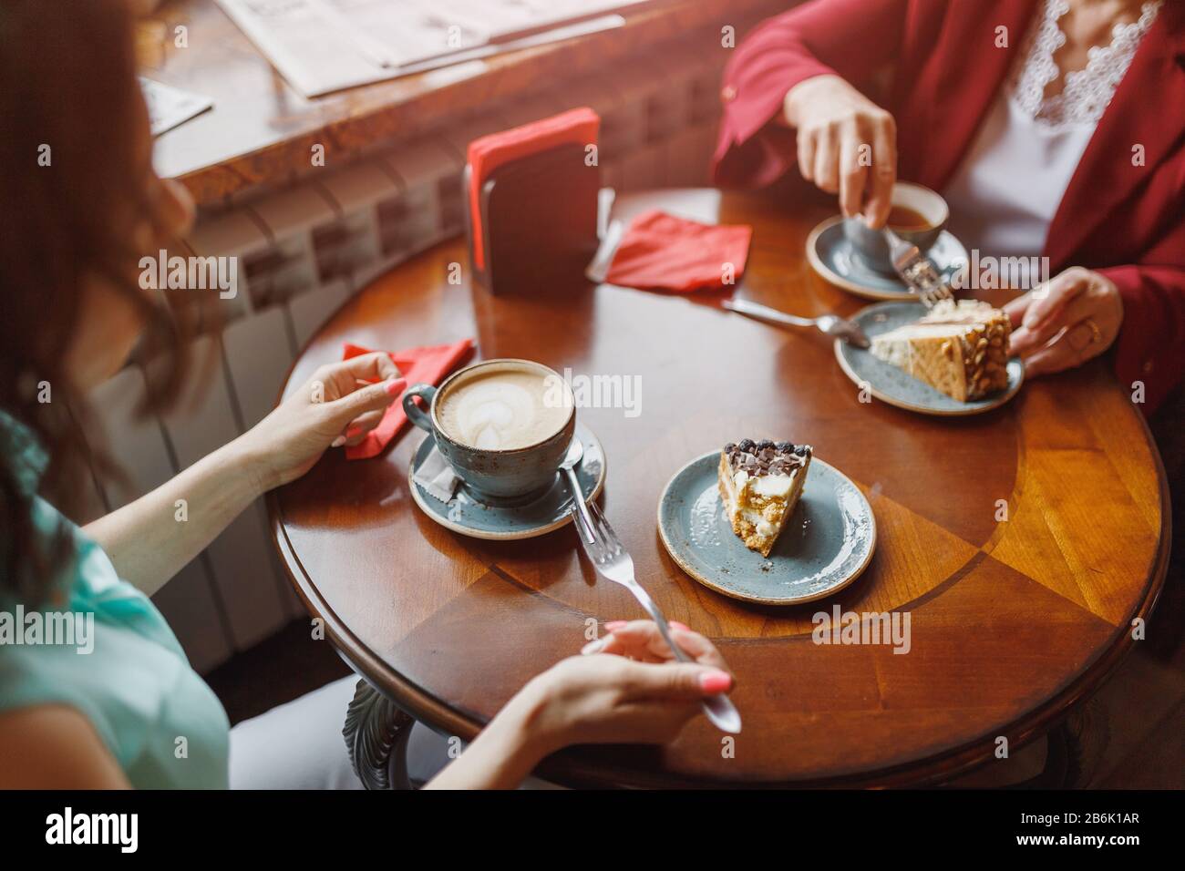 Two women chatting in a coffee shop, cake on the table Stock Photo - Alamy