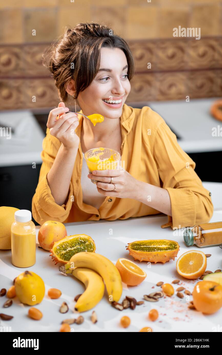 Young and cheerful woman eating chia pudding, having a snack or ...
