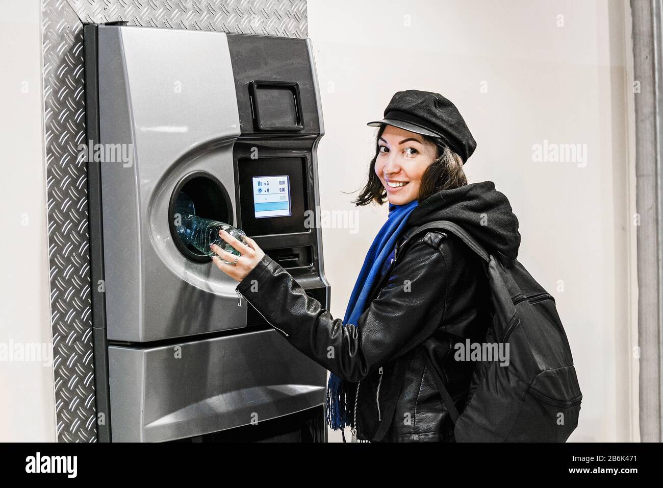 Woman throwing plastic and glass bottles in recycle automat terminal ...