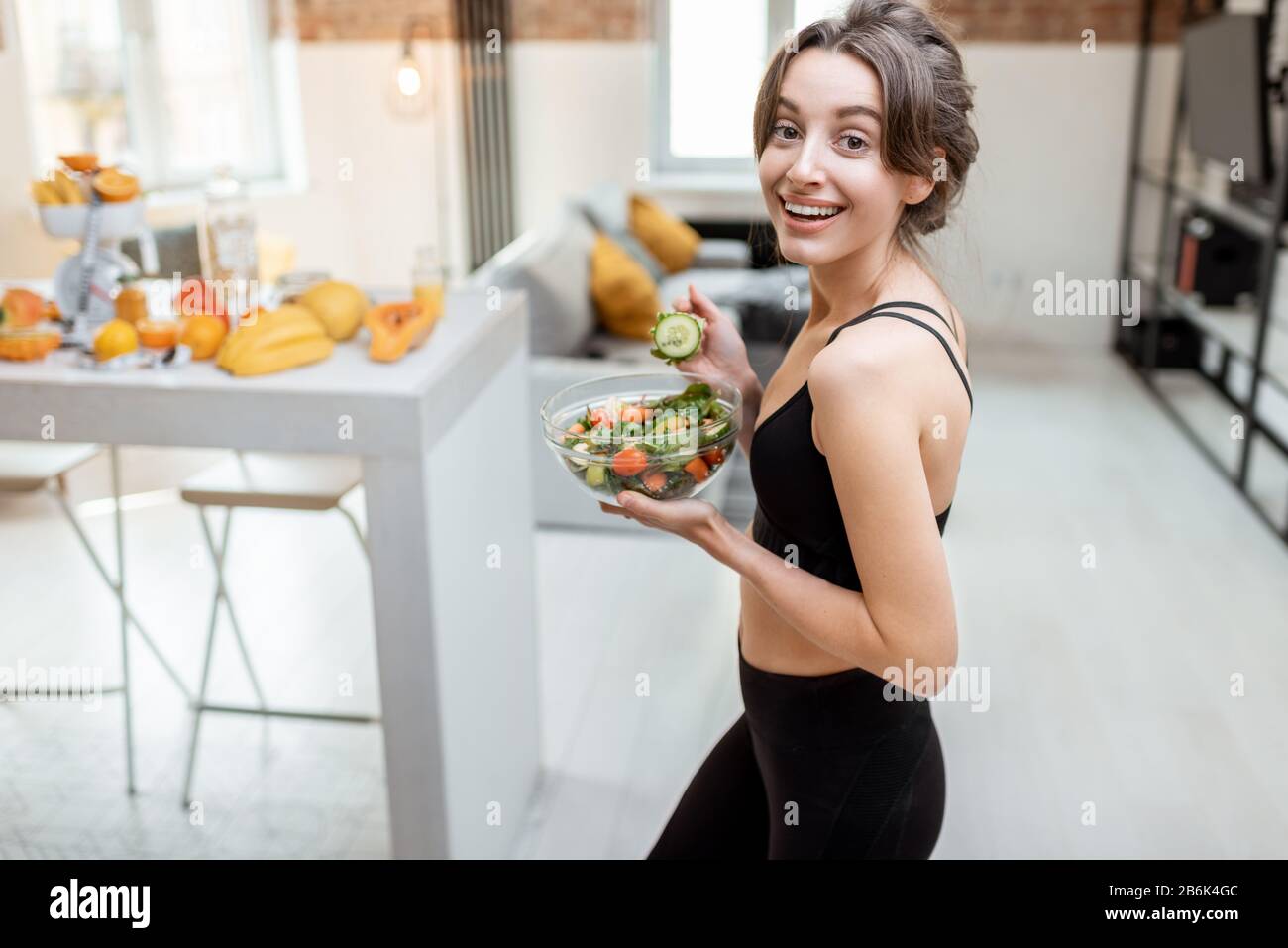 Portrait of a cheerful athletic woman eating healthy salad during a ...