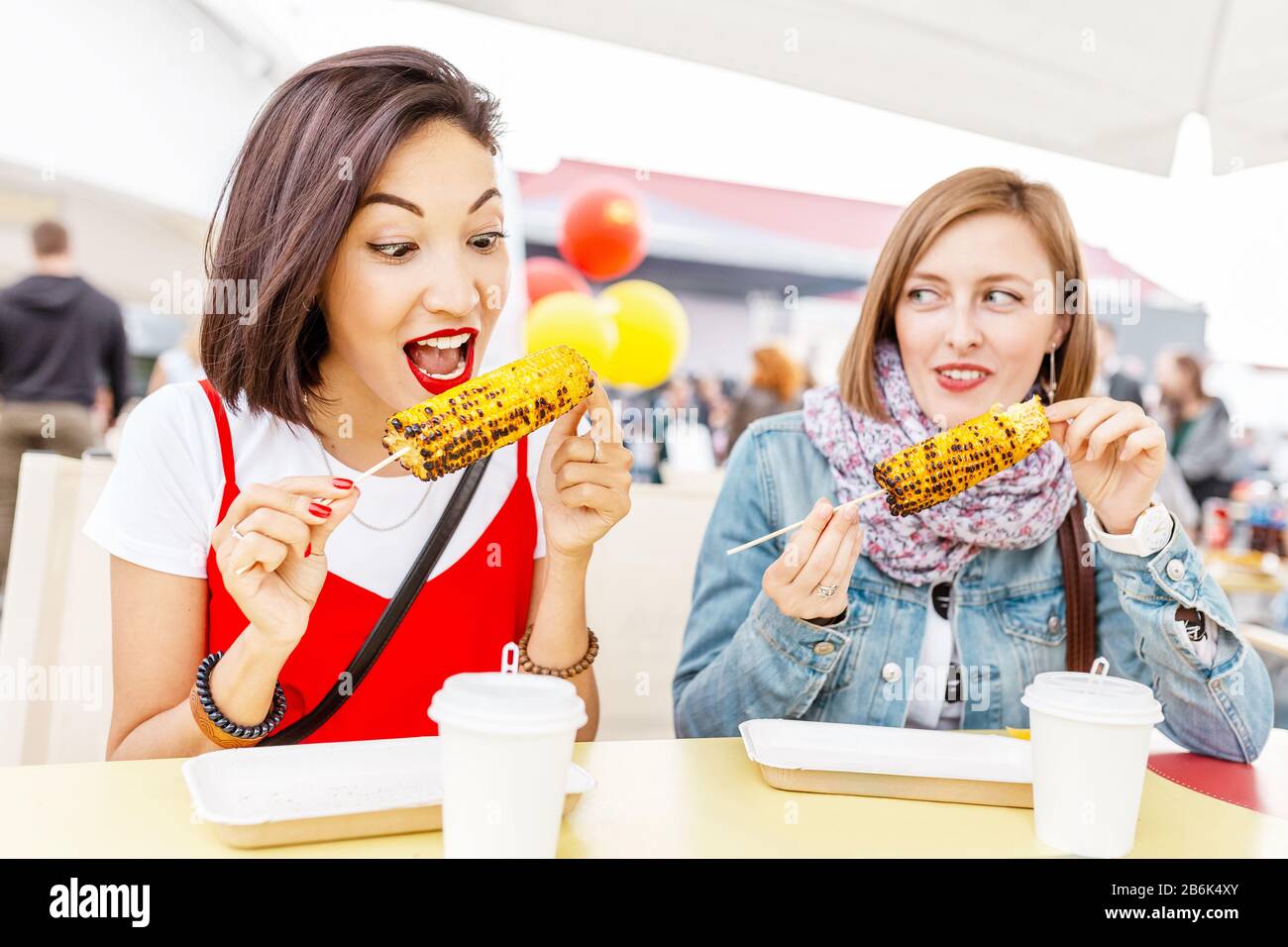 Woman friends eating street food corn at fastfood festival Stock Photo ...