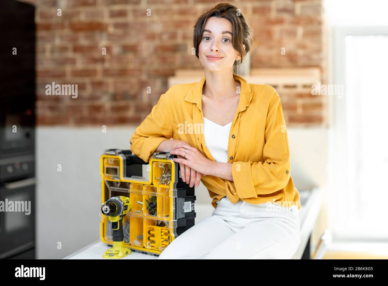 Portrait of a young and beautiful handy woman siting with instruments ...