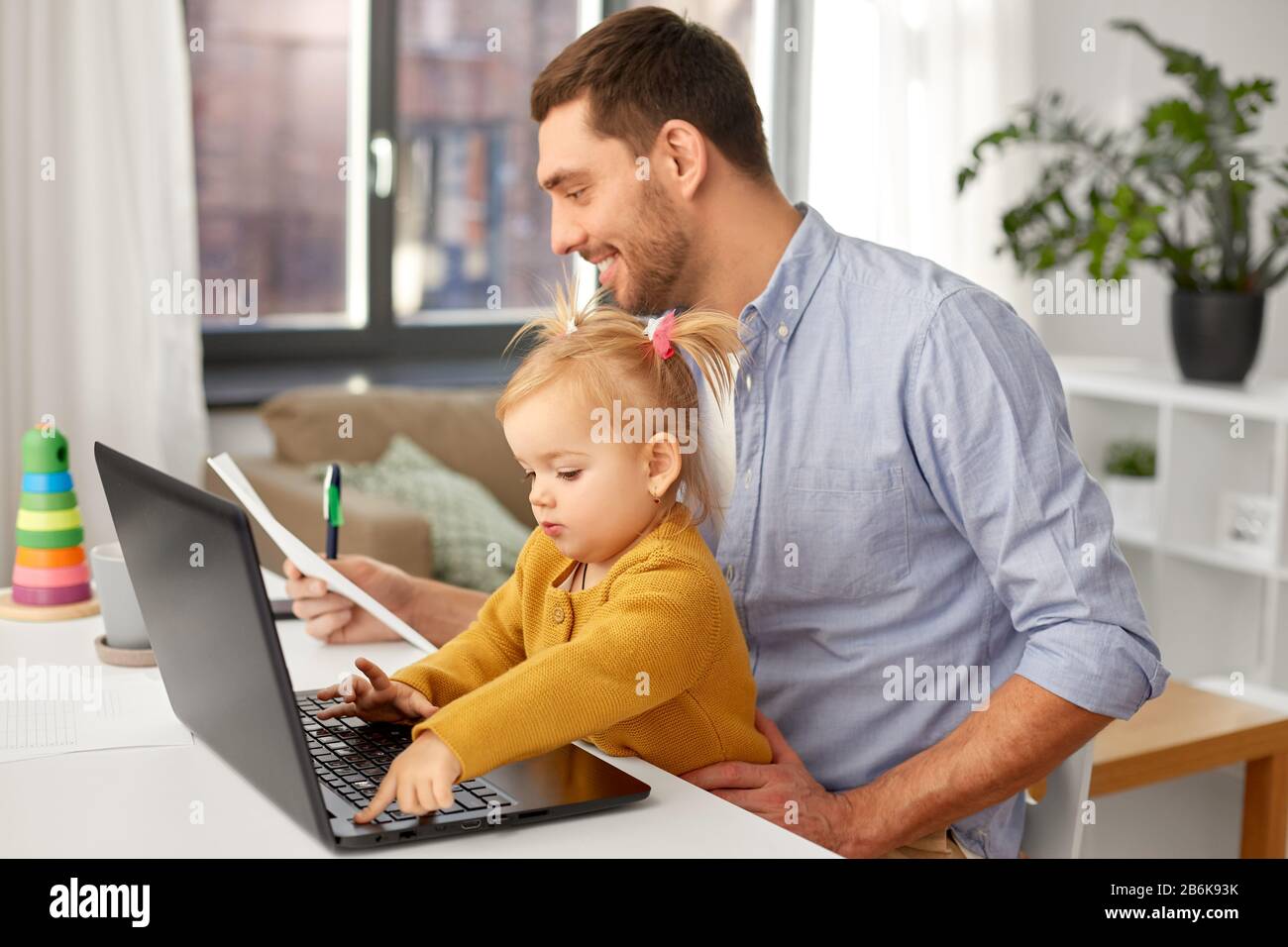 multi-tasking, freelance and fatherhood concept - working father with baby daughter and laptop ...