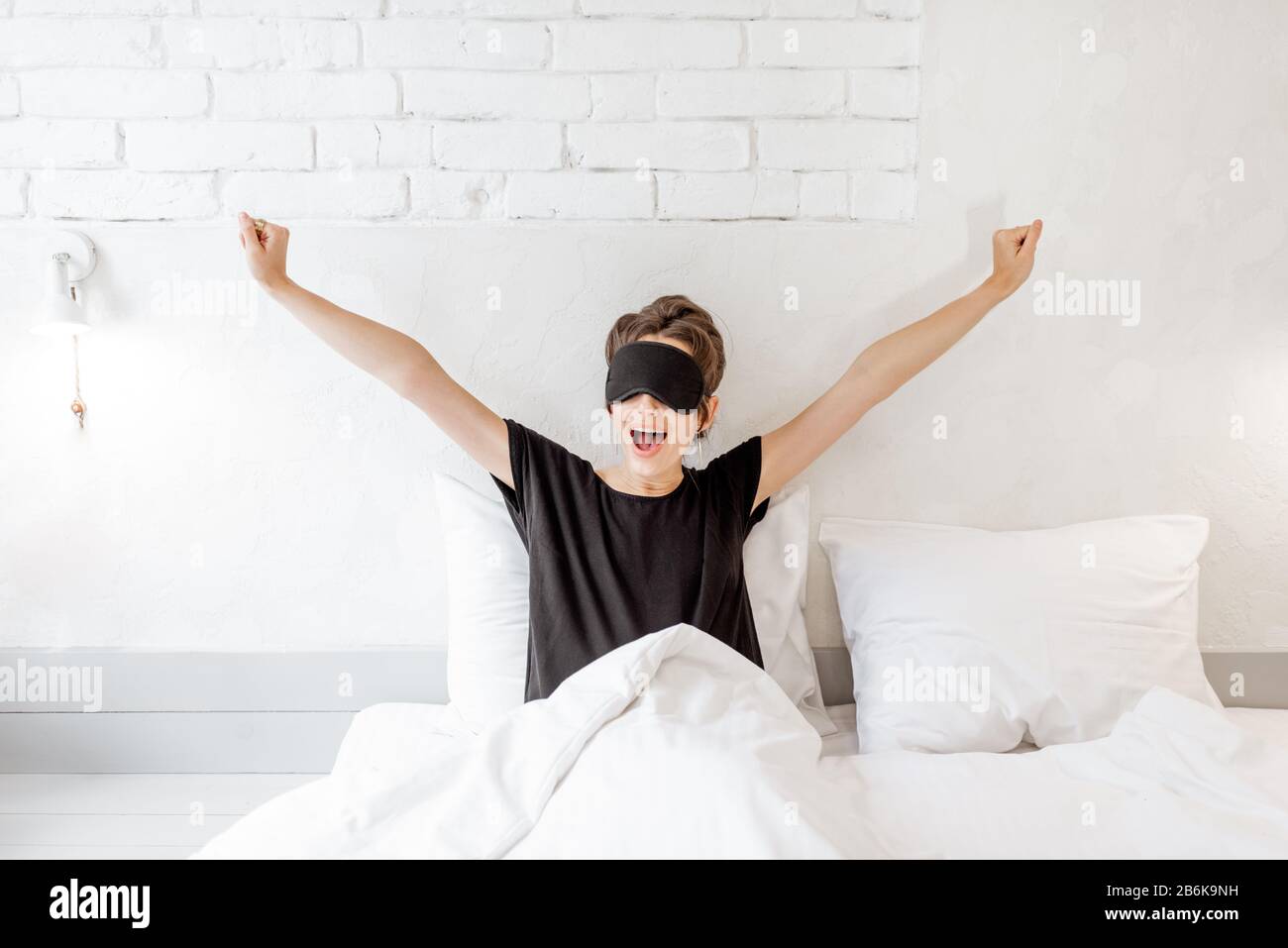 Young woman in sleeping mask waking up in the bedroom. Good morning ...