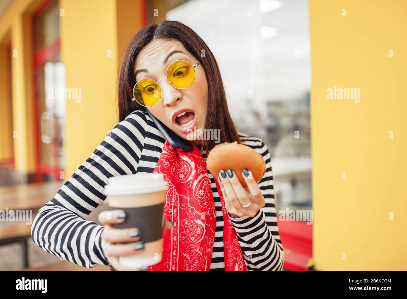 Surprised busy woman talking on the phone during a dinner at a fast ...