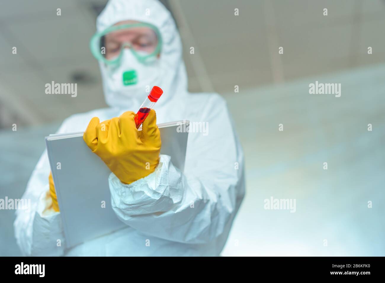 Virologist with blood test sample lab tube writing notes in virus ...