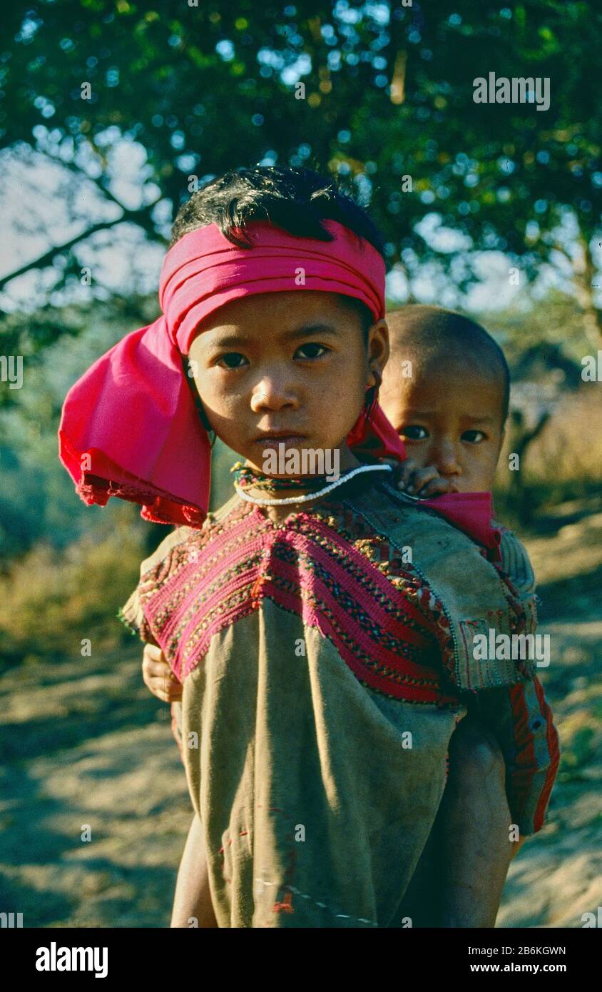 A young boy of the Lisu tribe carrying a baby on his back, wearing a ...