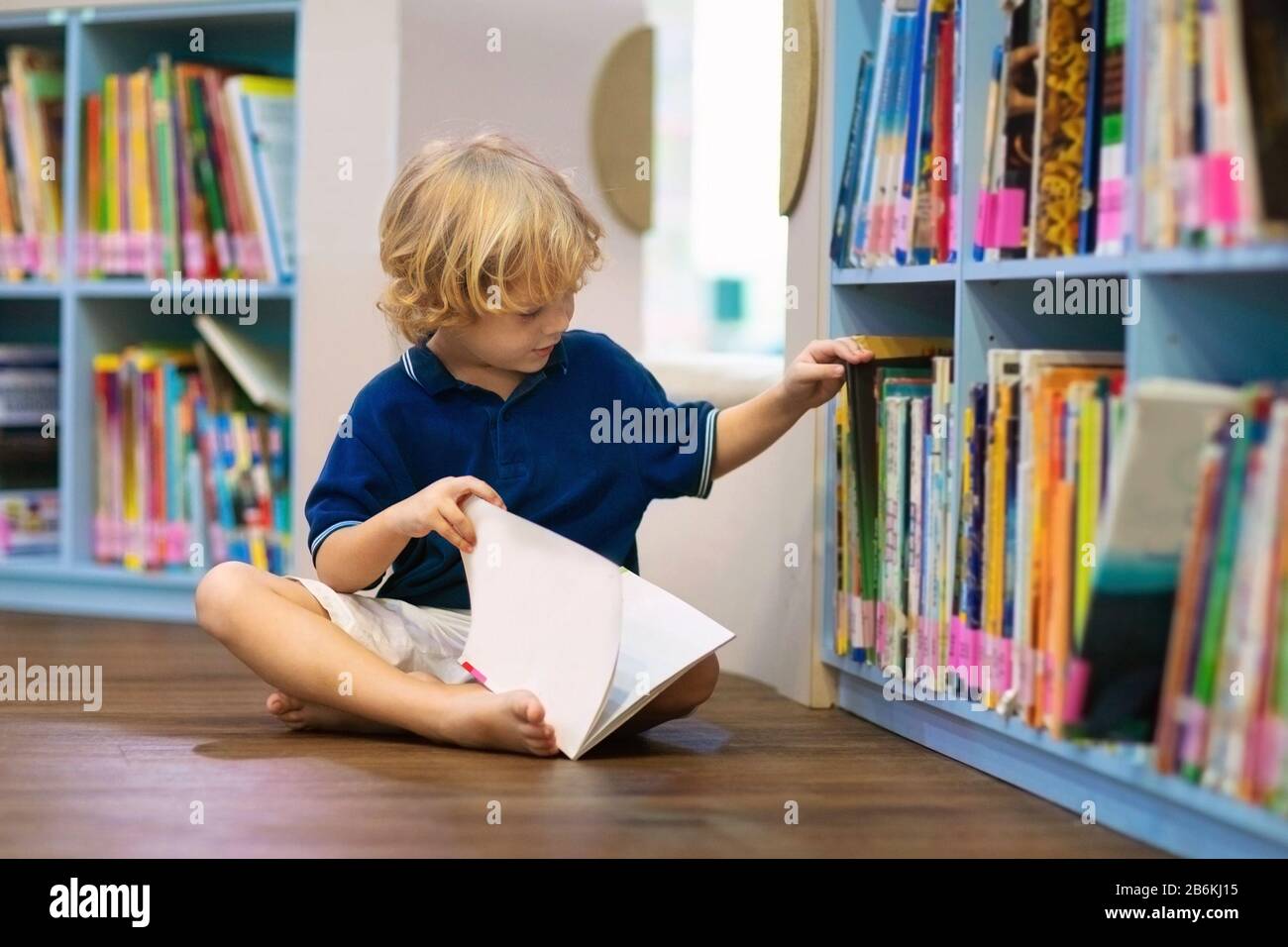 Child in school library. Kids read books. Little boy reading and ...