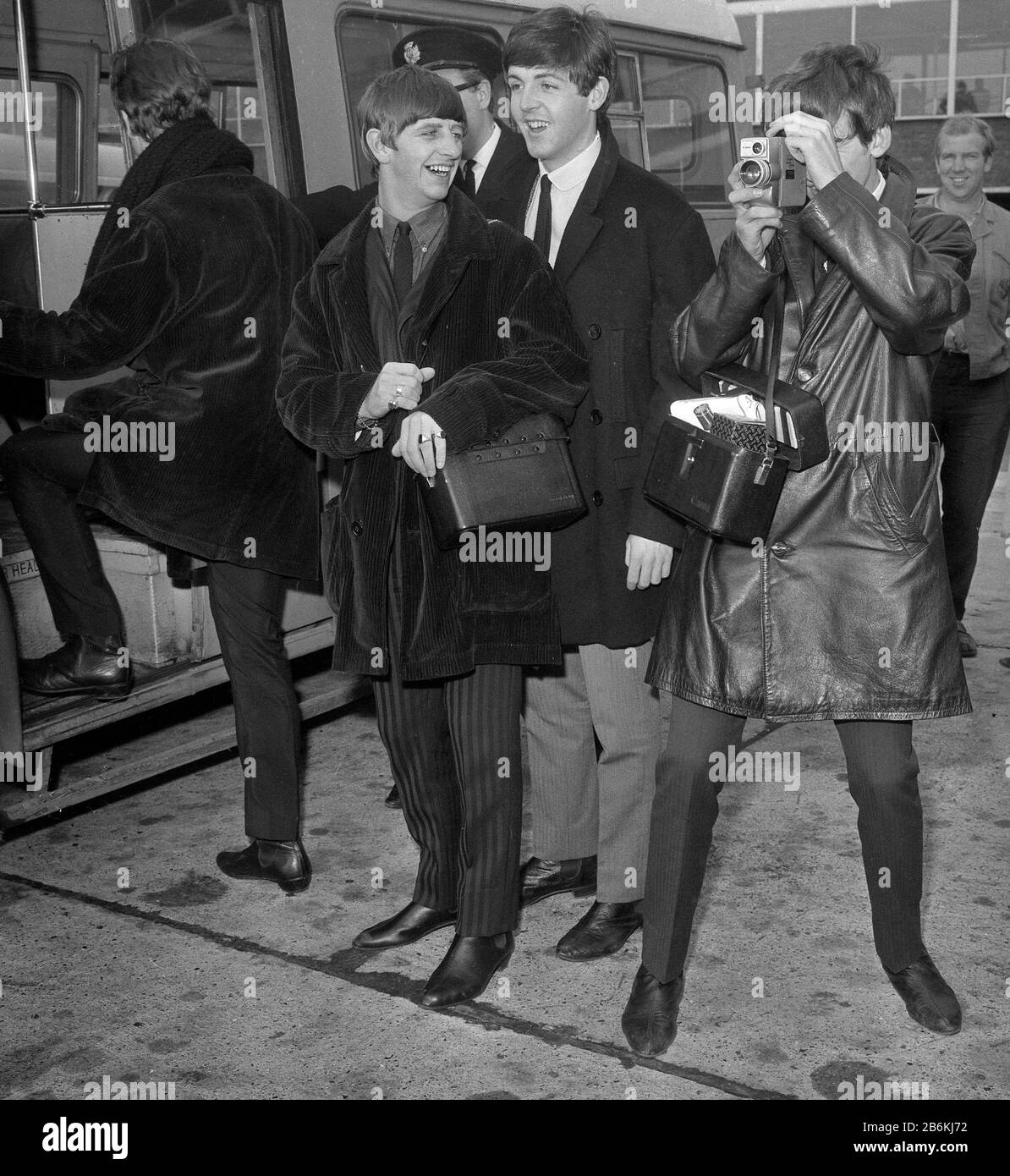 Left to right: John Lennon walks into the coach as Ringo Starr and Paul ...